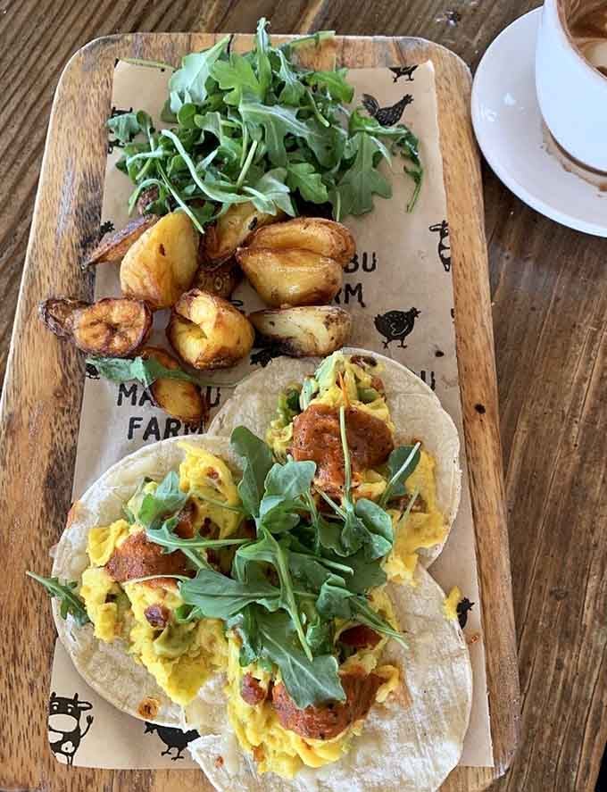 Breakfast tacos arrive on branded boards, stuffed with scrambled eggs and fresh arugula for morning magic.