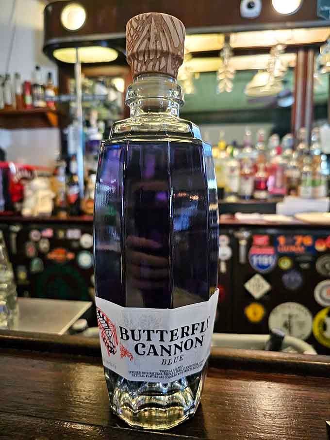 That distinctive blue bottle stands proud against the backbar, a modern spirit among the vintage souls who frequent this place.