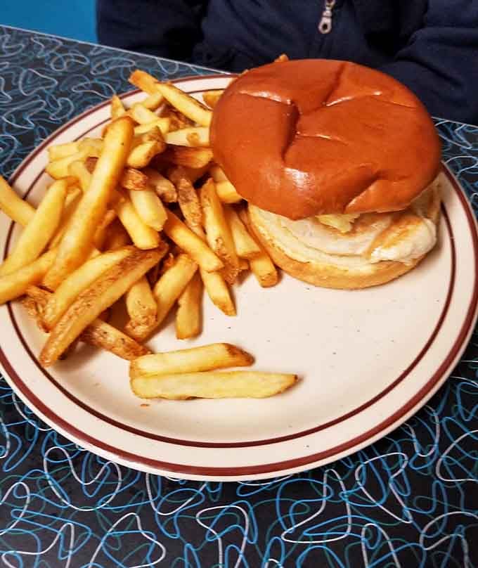That golden bun holds grilled chicken perfection, surrounded by fries that achieved the impossible: crispy outside, fluffy inside.