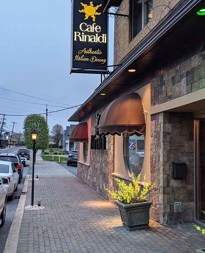 Caf&eacute; Rinaldi glows at dusk, its stone facade and copper awning beckoning hungry travelers into Old Forge's delicious pizza tradition.