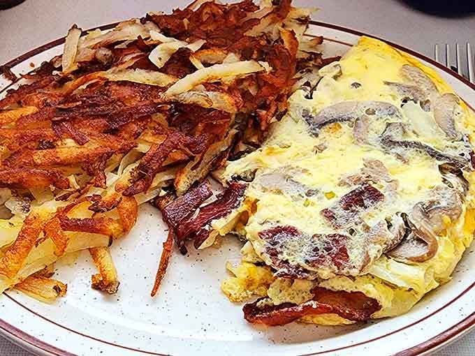 That omelet is stuffed with more mushrooms than a fairy tale forest, paired with hash browns that crunch like autumn leaves.