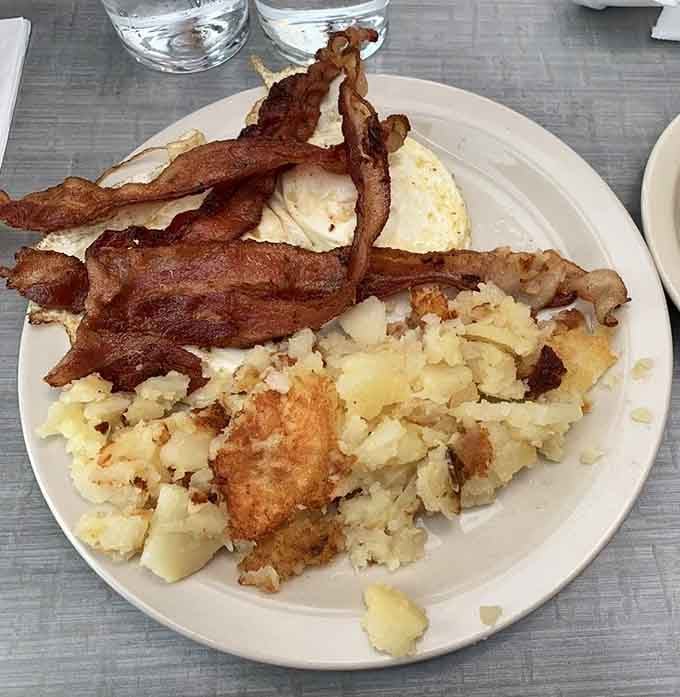 Crispy bacon standing at attention over eggs and hash browns; this is how breakfast earns its most important meal status.