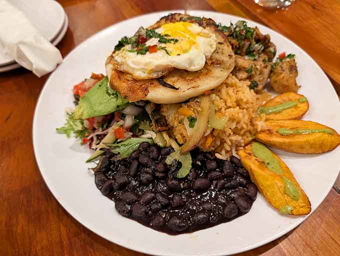 That fried egg perched on top like a crown proves breakfast-for-dinner rules don't apply when Caribbean cuisine is involved.