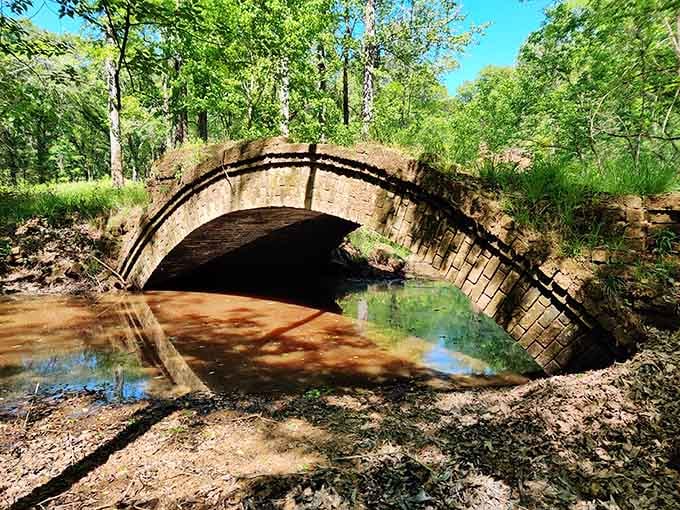 This stone arch bridge defies gravity and time, stubbornly refusing to collapse despite nature's best efforts at demolition.