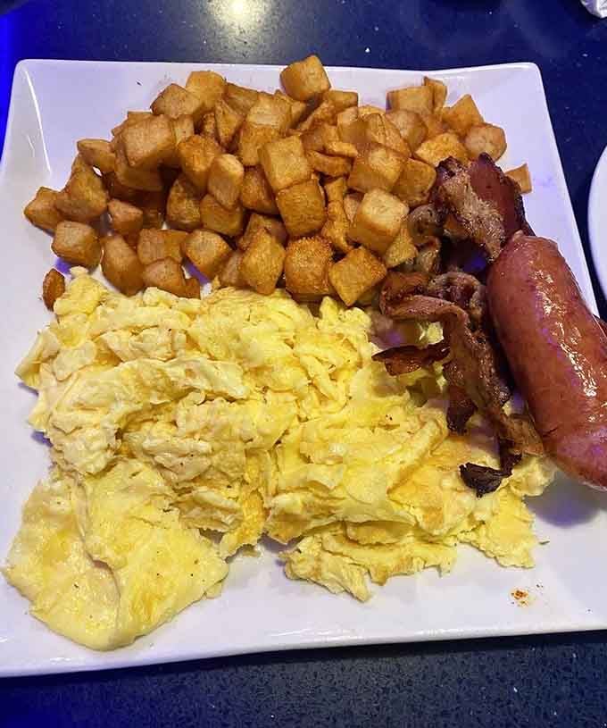 Scrambled eggs, crispy home fries, and breakfast meats arranged like edible architecture on a plate of pure satisfaction.