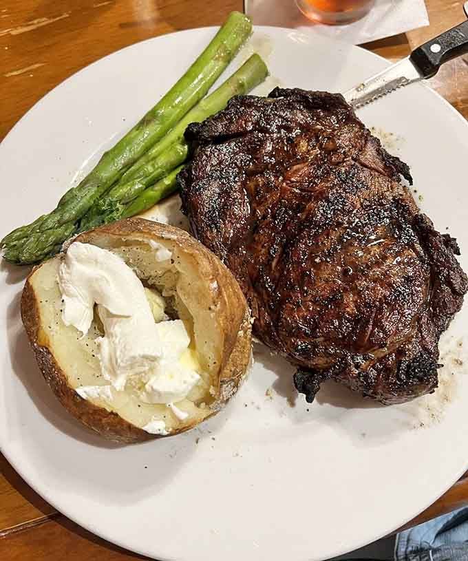 A ribeye this beautifully charred deserves its own standing ovation, asparagus and baked potato included.