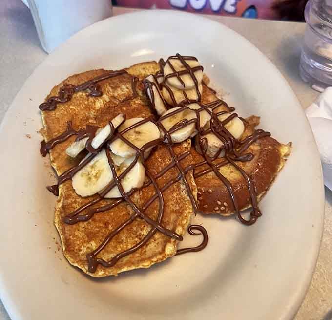 Pancakes topped with bananas and chocolate drizzle: because adulting means ordering dessert for breakfast.