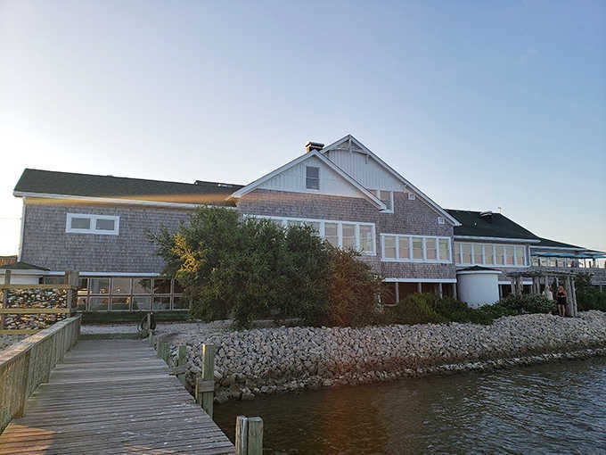 The wooden boardwalk leads to a classic coastal restaurant where sunset views compete with the seafood for attention.