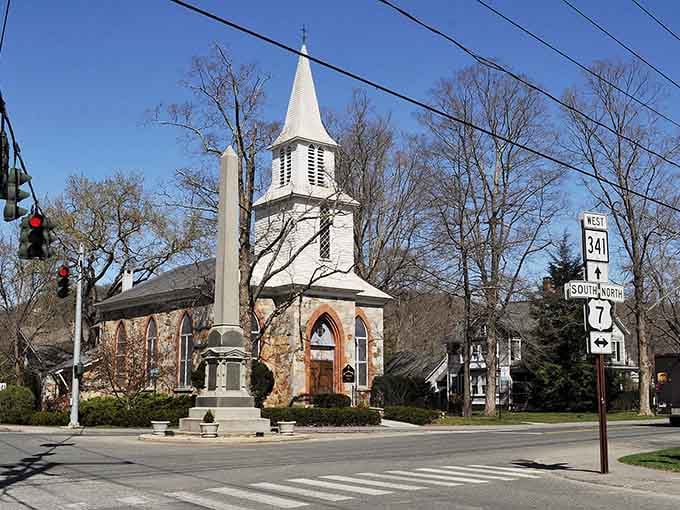 A stone church and monument anchor this intersection where history literally stands at the crossroads watching traffic pass.