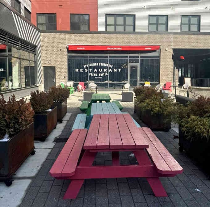 Colorful picnic tables create a playful outdoor dining scene that makes steak night feel like summer camp.