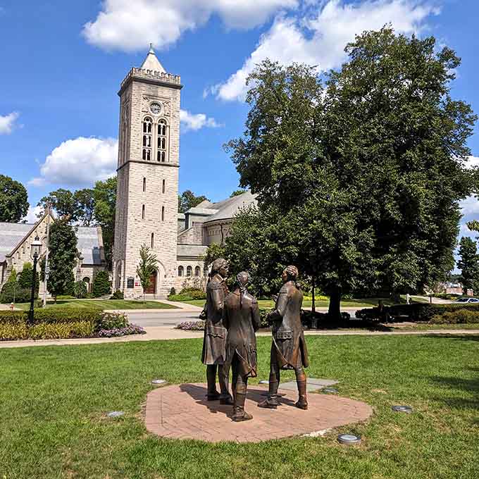 The bell tower stands tall while bronze figures gather below, honoring history in this beautifully maintained public space.