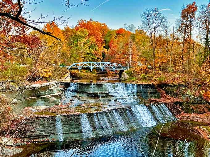 Water spreads wide across shale layers like a liquid curtain in this autumn-framed natural masterpiece.