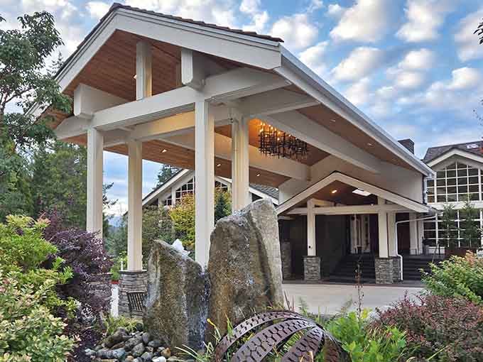 Water features and stone columns frame this elegant entrance, where Northwest craftsmanship meets spa-worthy luxury and waterfall thunder.