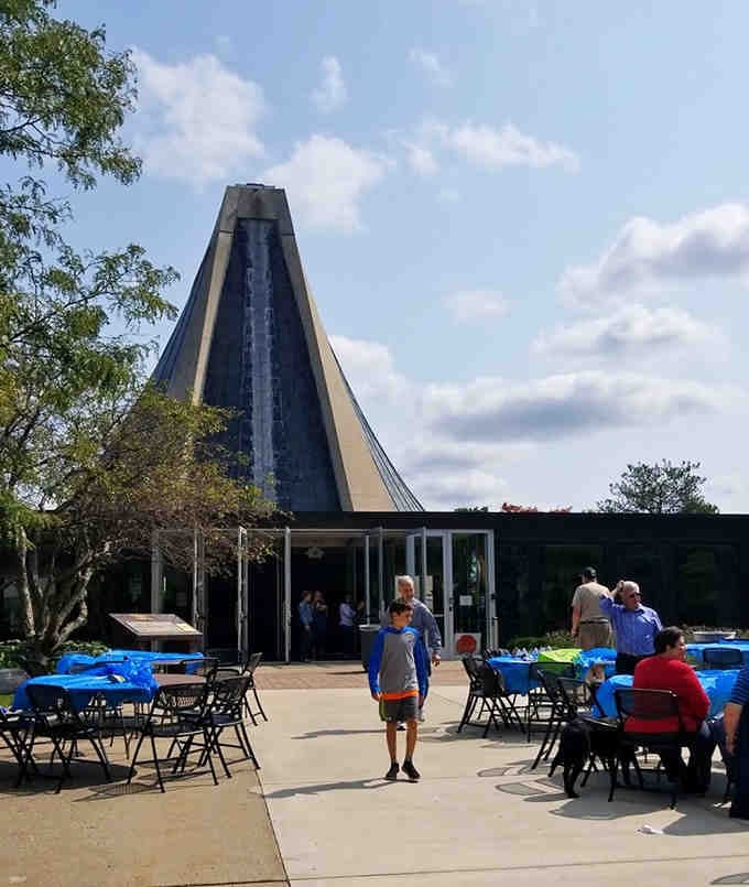 The pyramid rises dramatically, its dark surfaces creating a striking silhouette against bright blue Michigan skies.