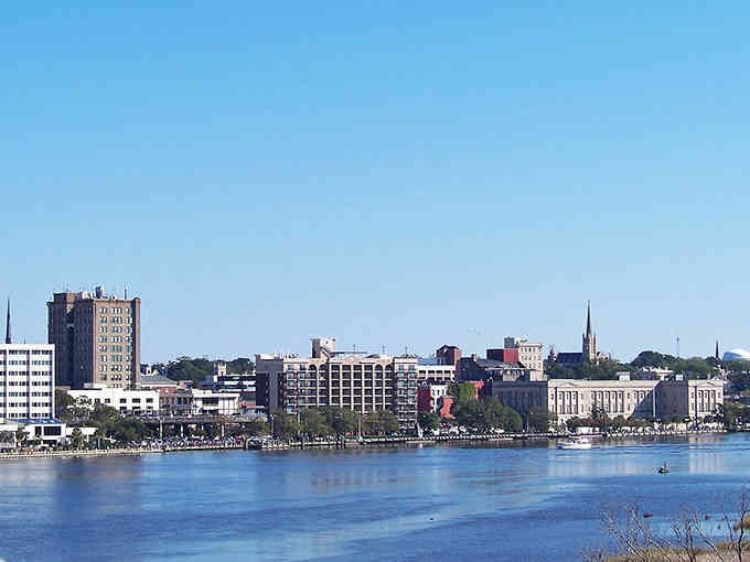 Wilmington's skyline rises from the Cape Fear River, blending historic church steeples with modern towers in perfect harmony.