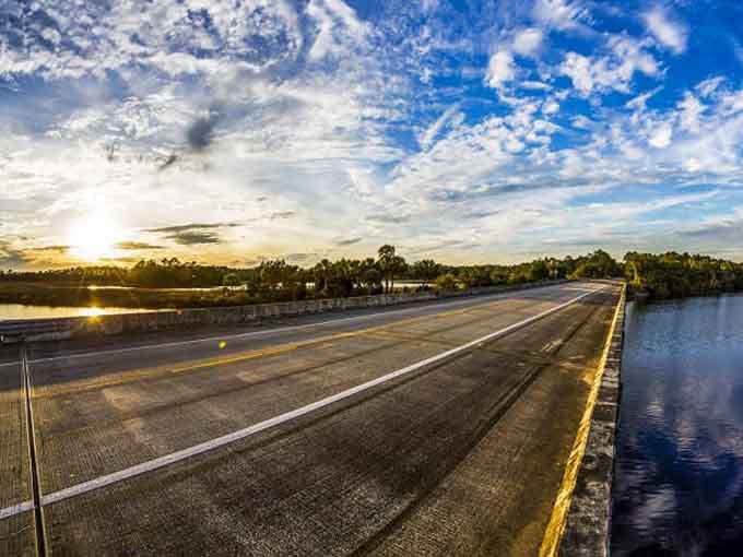 Golden hour transforms this waterway crossing into pure magic, with sunset colors painting the sky and reflecting off the calm surface below.