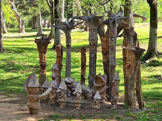 Wooden faces peer from carved trunks like friendly forest spirits welcoming visitors to their enchanted woodland home.