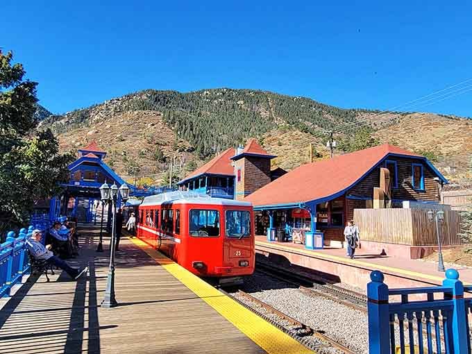 Colorful station buildings frame this sleek red train perfectly, creating a postcard-worthy scene that practically begs for a photograph.