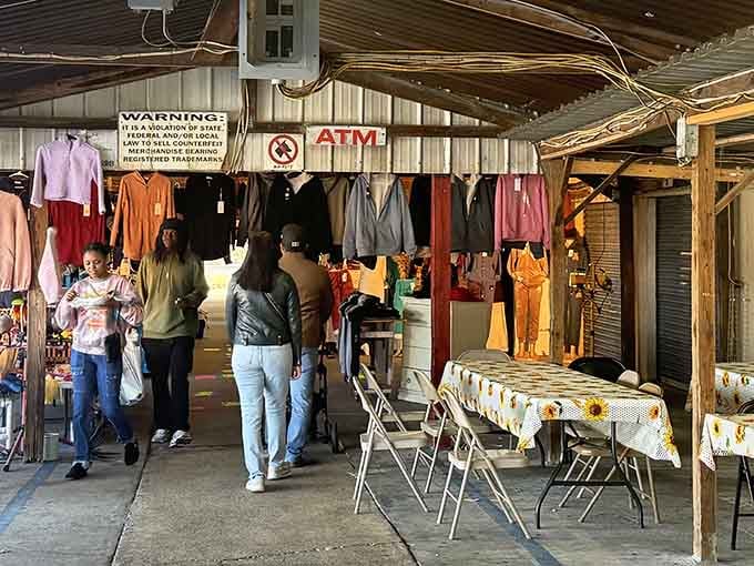 Shoppers browse beneath hanging clothing while natural light streams in, creating an inviting marketplace atmosphere.