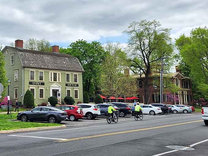 Historic buildings frame a bustling street where cyclists and cars share the road in perfect small-town harmony and mutual respect.