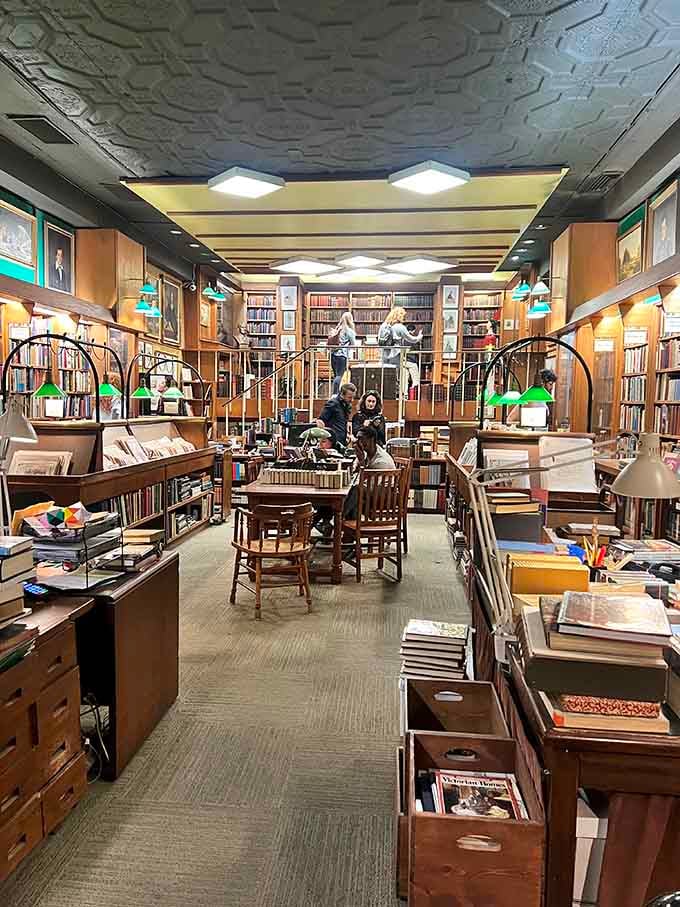 Serious browsers navigate aisles under that decorative ceiling, hunting literary gold like Indiana Jones with reading glasses on.