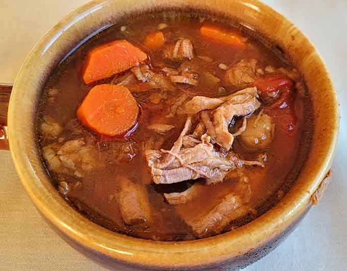 Hearty beef and vegetable soup in a proper crock, the kind that warms you from the inside out.