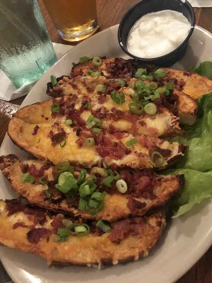 Potato skins loaded with cheese, bacon, and green onions deliver comfort food happiness in every crispy, indulgent bite.