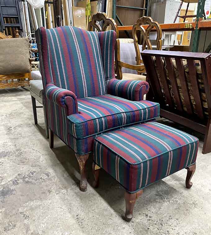 That striped wingback chair with ottoman combo is giving serious cozy reading nook vibes from another era.