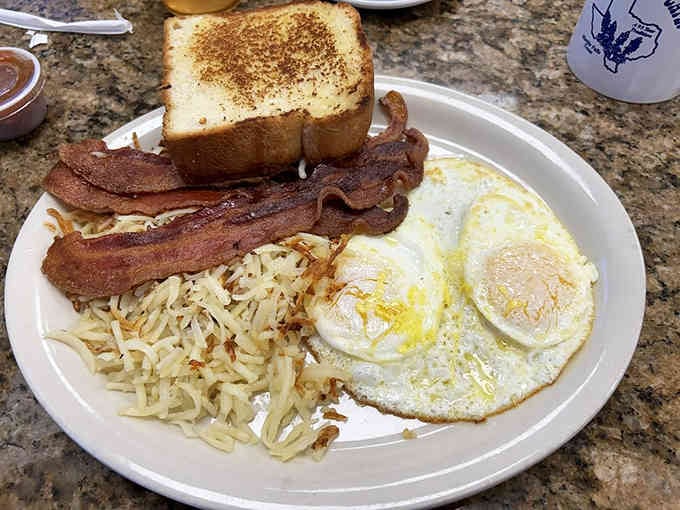 Crispy bacon, sunny eggs, and hash browns golden enough to make your cardiologist weep with professional concern.