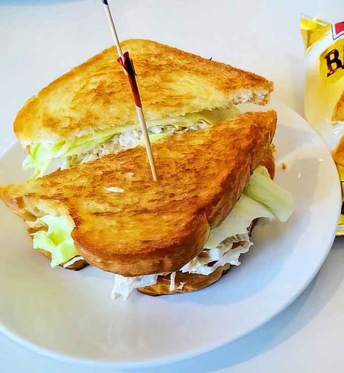Toasted bread cradling chicken salad perfection, served with hash browns that could convert even the staunchest breakfast-hater to morning meals.