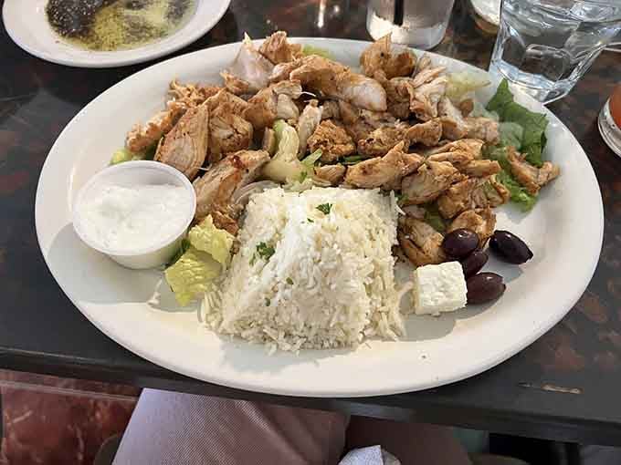 The chicken shawarma platter delivers generous portions of marinated, grilled chicken over rice with kalamata olives and creamy feta cheese.