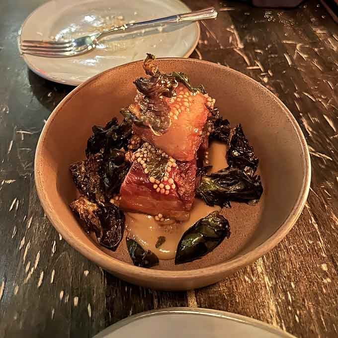 Crispy pork belly nestled with Brussels sprouts creates the kind of harmony that makes vegetarians momentarily reconsider everything.