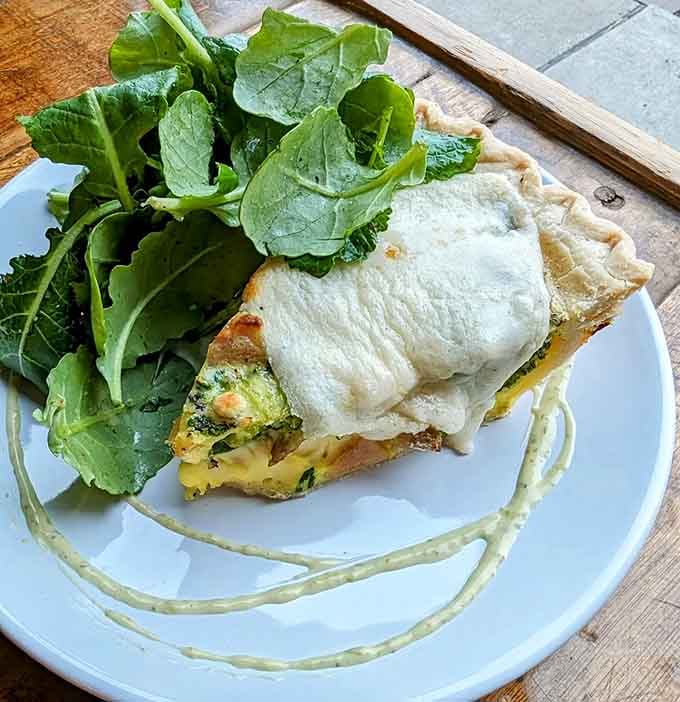 Quiche served with fresh greens, proving that brunch done right can make you feel fancy without trying too hard.