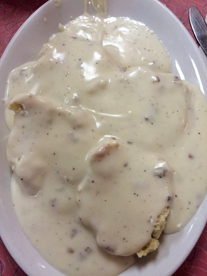 Creamy, peppery gravy cascading over tender biscuits like a delicious avalanche of Southern comfort on a plate.