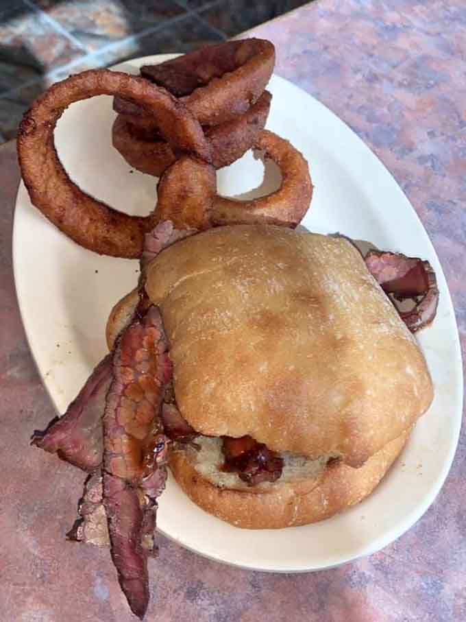 Brisket sandwich with onion rings proving that sometimes the best decisions involve choosing both options simultaneously.