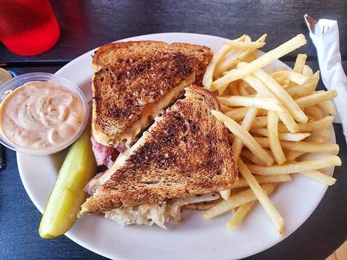 The Reuben sandwich arrives golden and crispy, proving that some classics never need improvement, just appreciation.