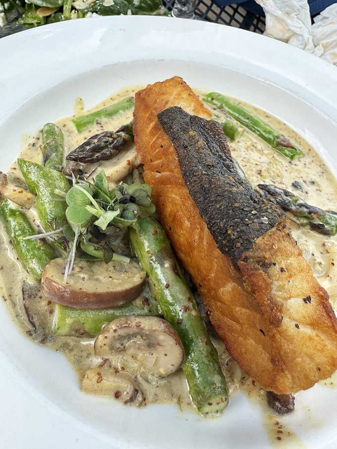 Crispy-skinned salmon nestled among fresh asparagus and mushrooms in a creamy sauce that dreams are made of.