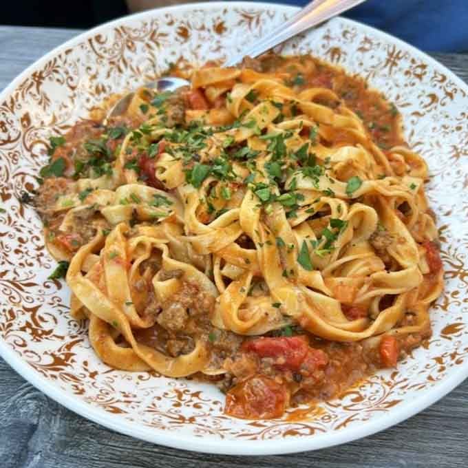 Fresh pasta ribbons tangled with hearty Bolognese sauce, finished with herbs that make everything taste like Sunday dinner.