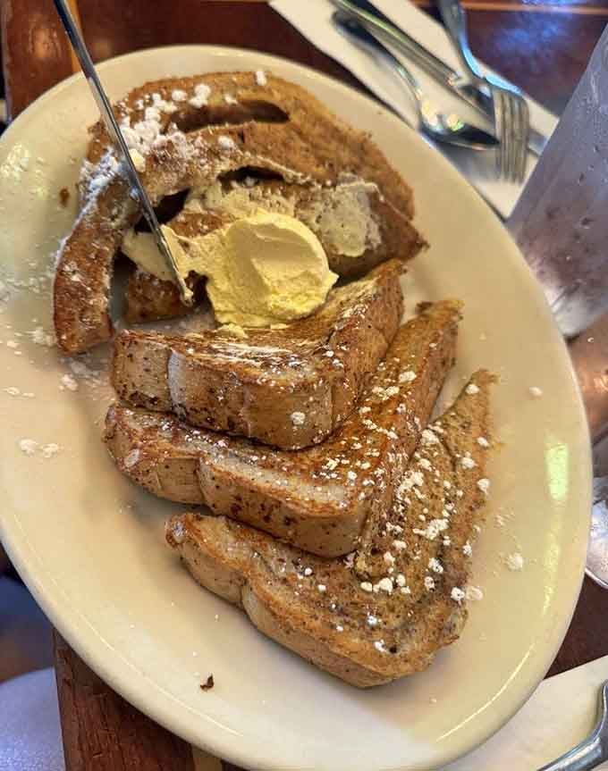 French toast dusted with powdered sugar and butter melting on top, exactly as the breakfast gods intended it.