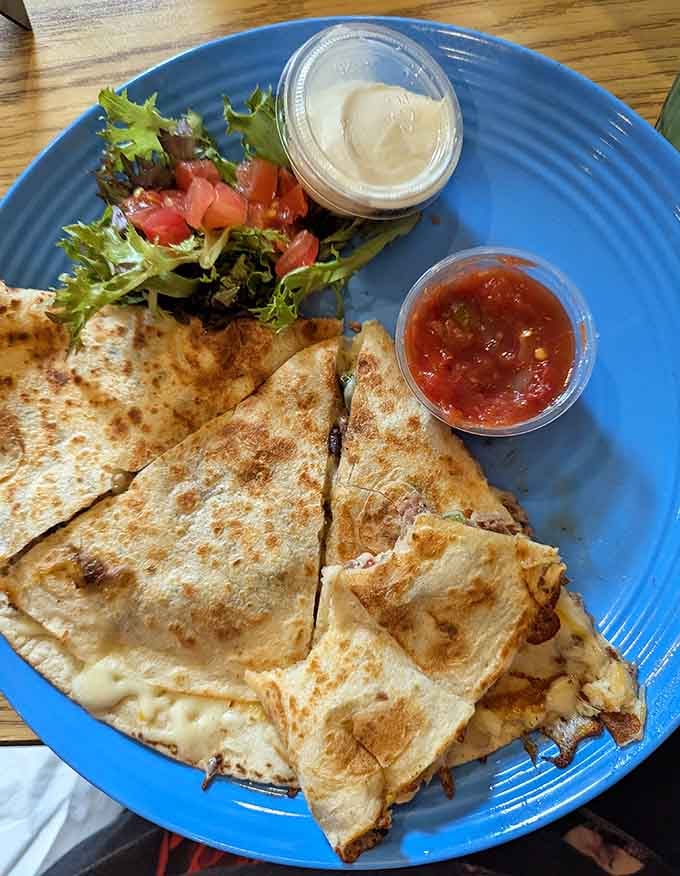 Golden quesadilla wedges hide melted cheese treasures inside, accompanied by fresh greens and zesty salsa for dipping pleasure.