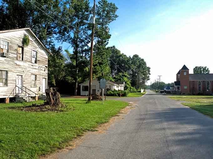 Even the street looks uncertain about its purpose, stretching between structures that can't decide whether to stand or finally give up.