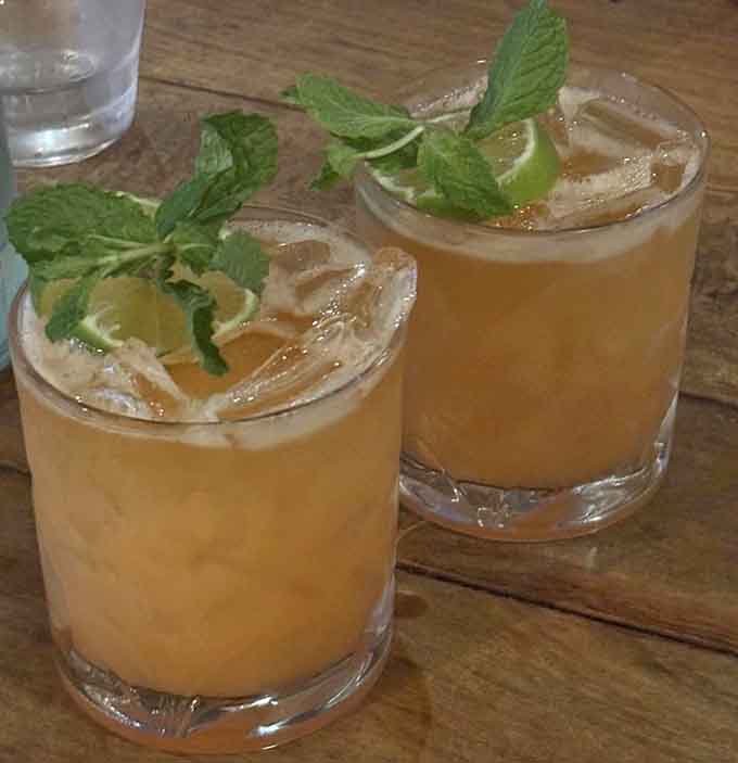 Fresh mint sprigs and citrus wedges floating in those amber cocktails practically whisper "happy hour" in your ear.