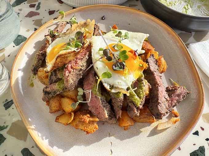 Steak and eggs topped with sunny-side perfection, proving that some classics never need fixing, just excellent execution.