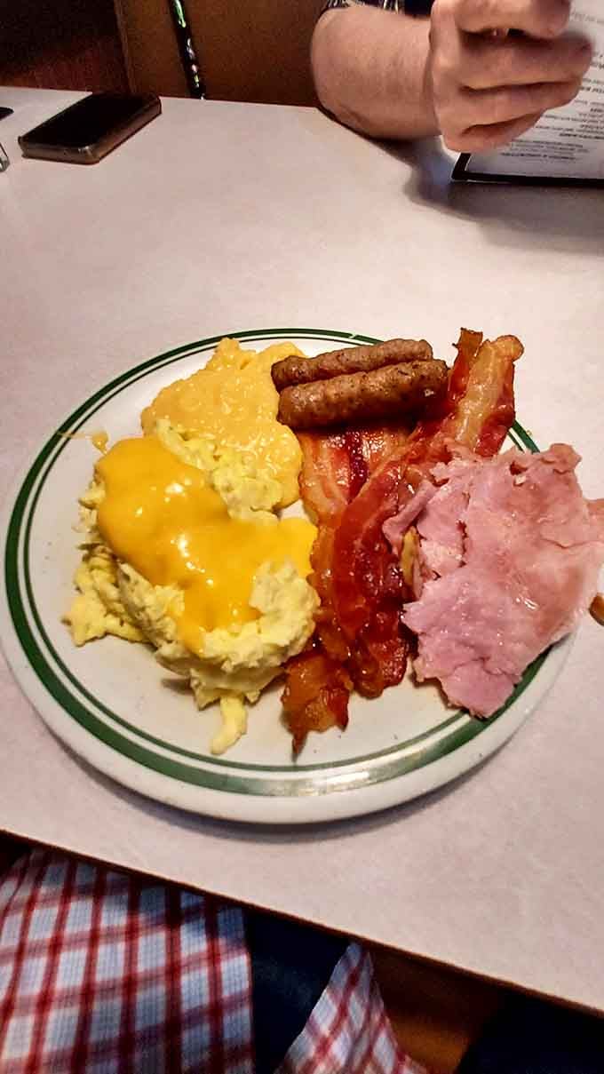 Scrambled eggs, bacon, sausage links, and ham create a protein-packed breakfast that laughs at portion control and wins.