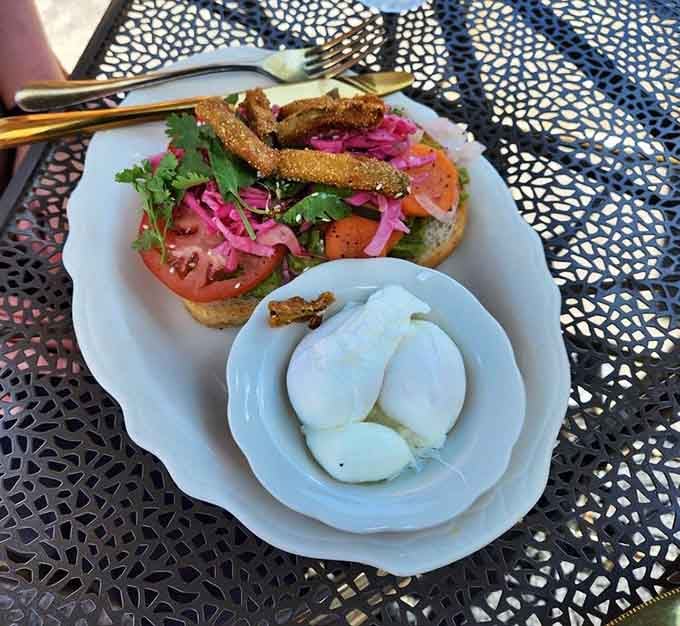 Fried avocado crowns this colorful creation where pickled vegetables and fresh tomatoes turn toast into a work of art.