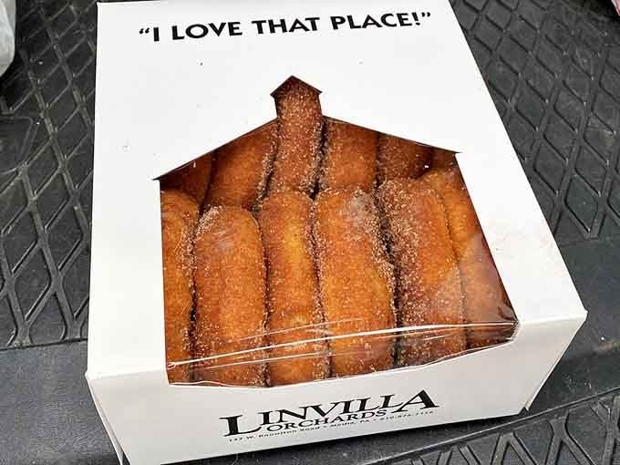 Several golden apple cider donuts in a box that says "I Love That Place!" which is underselling it, honestly.