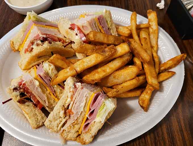 That towering club sandwich isn't messing around, stacked high enough to require architectural planning before the first bite.