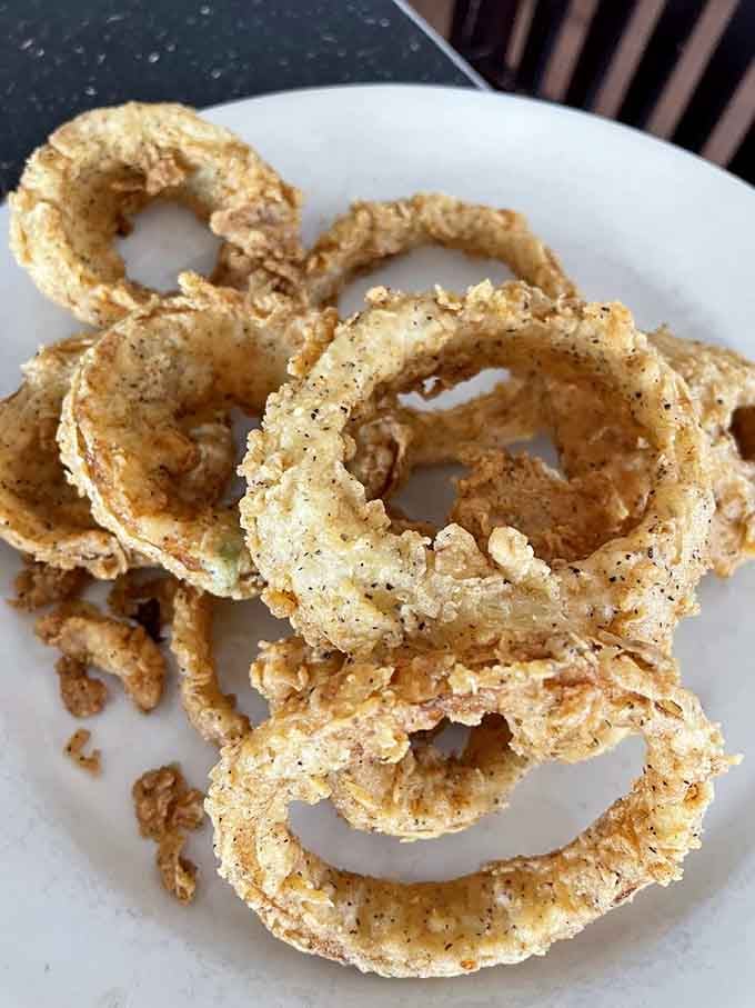 Onion rings stacked like edible architecture, crispy golden circles of pure fried joy and zero regrets.