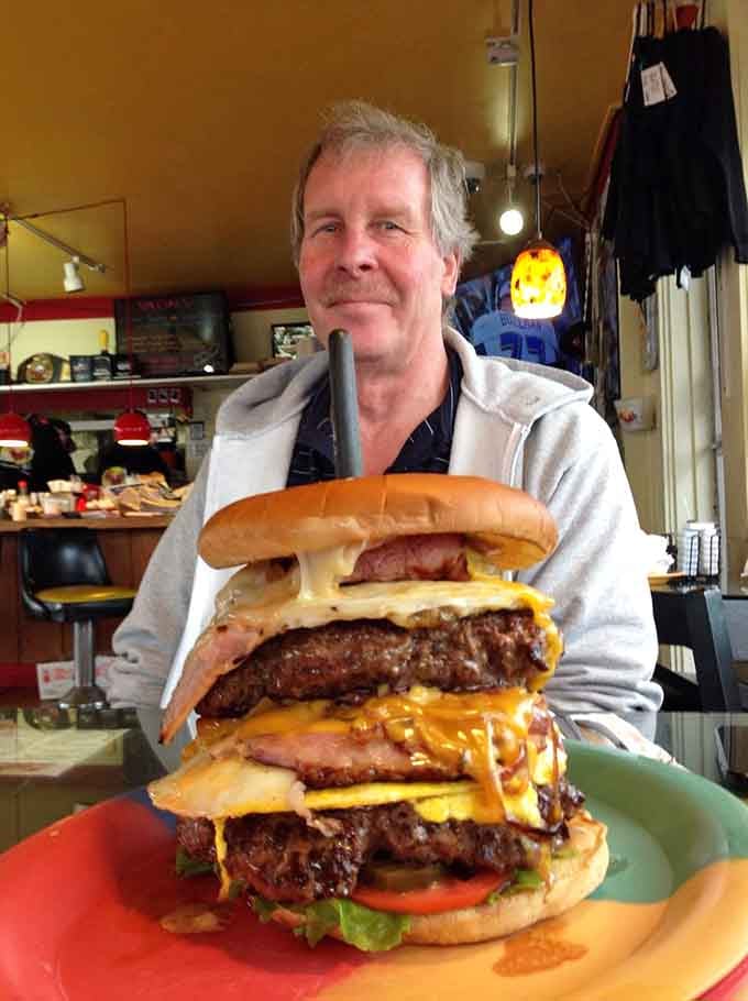 Three patties, multiple cheese slices, and the kind of ambition that makes cardiologists nervous but taste buds ecstatic beyond measure.