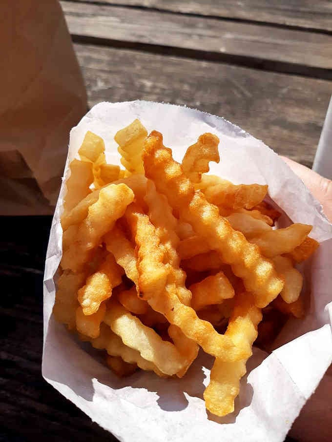 Crinkle-cut fries catching the light like edible gold, crispy ridges holding just enough salt to make you reach for more.